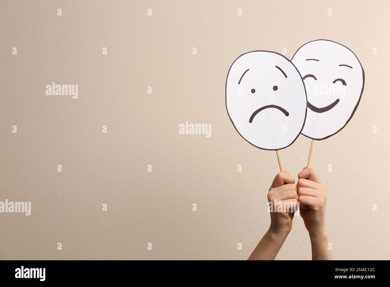 Woman with sad and happy paper faces on beige background, closeup ...