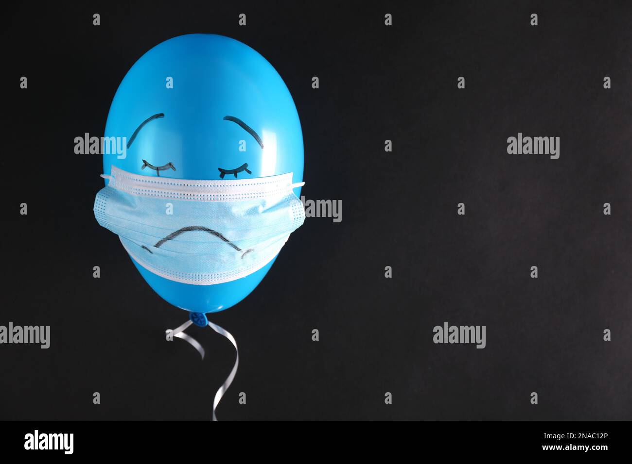 Air balloon in medical mask with drawn sad face on black background ...