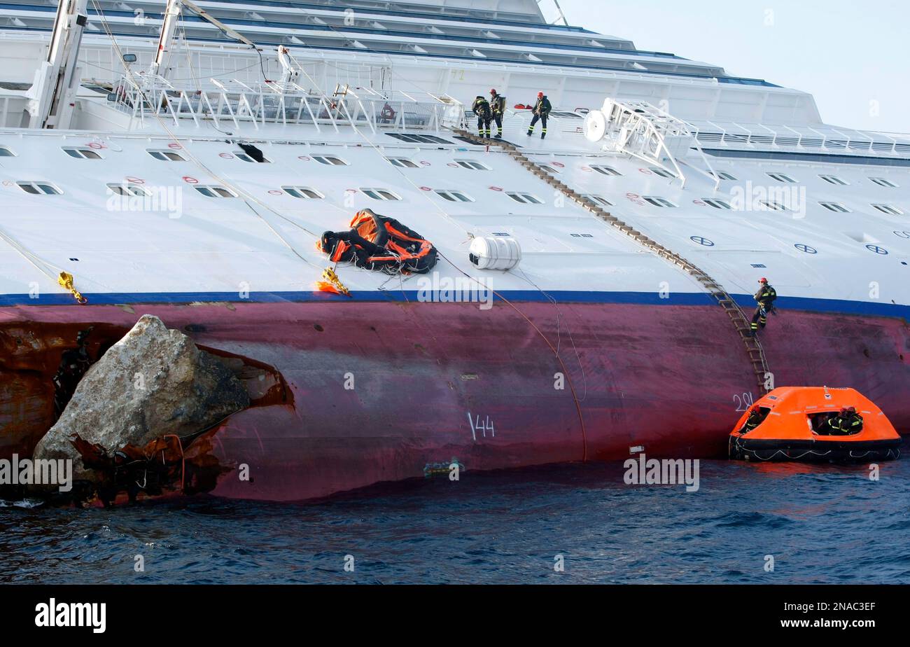 Italian firefighters work on the hull of the grounded cruise ship Costa ...