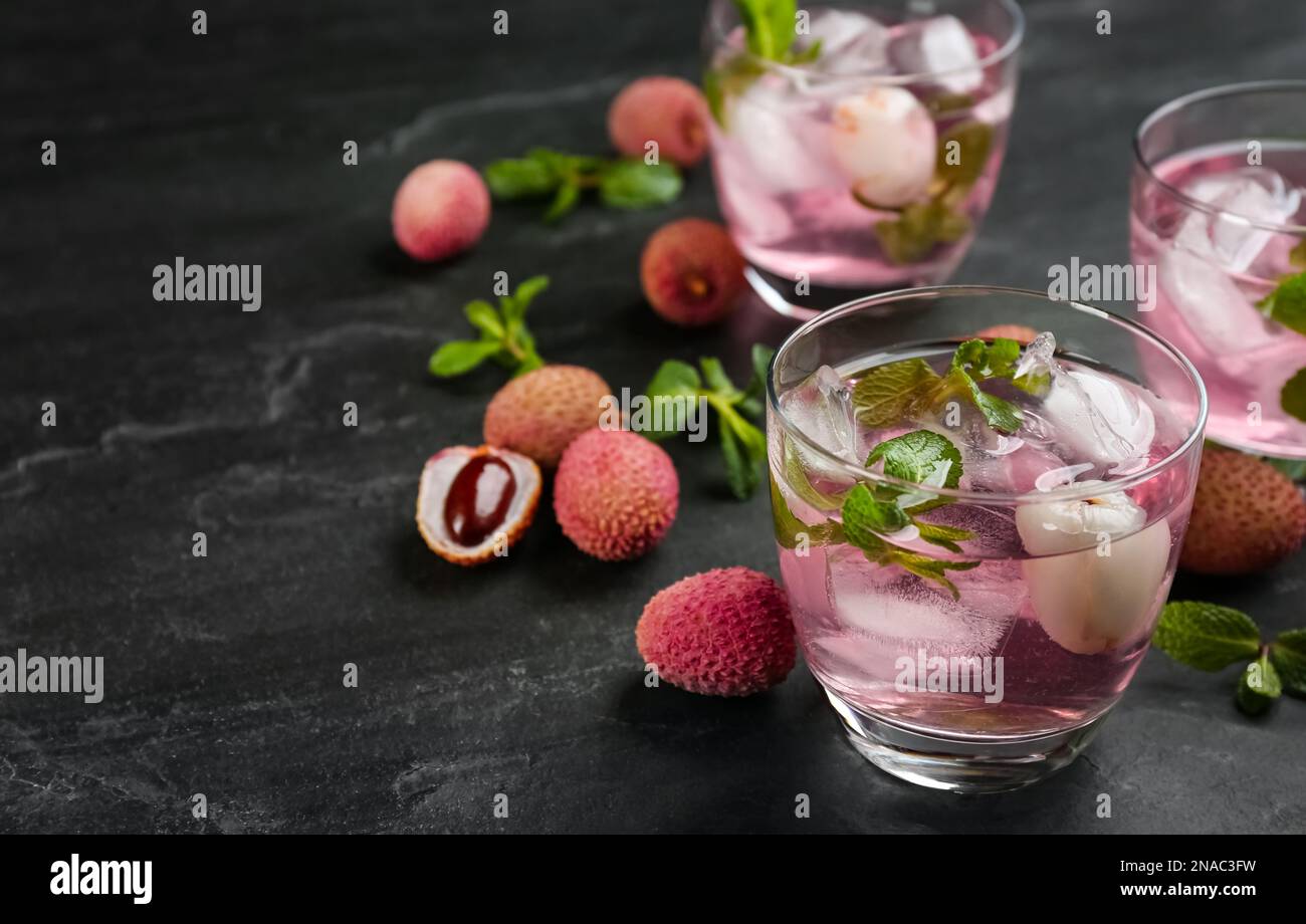 Delicious lychee cocktails with mint and fresh fruits on black table ...