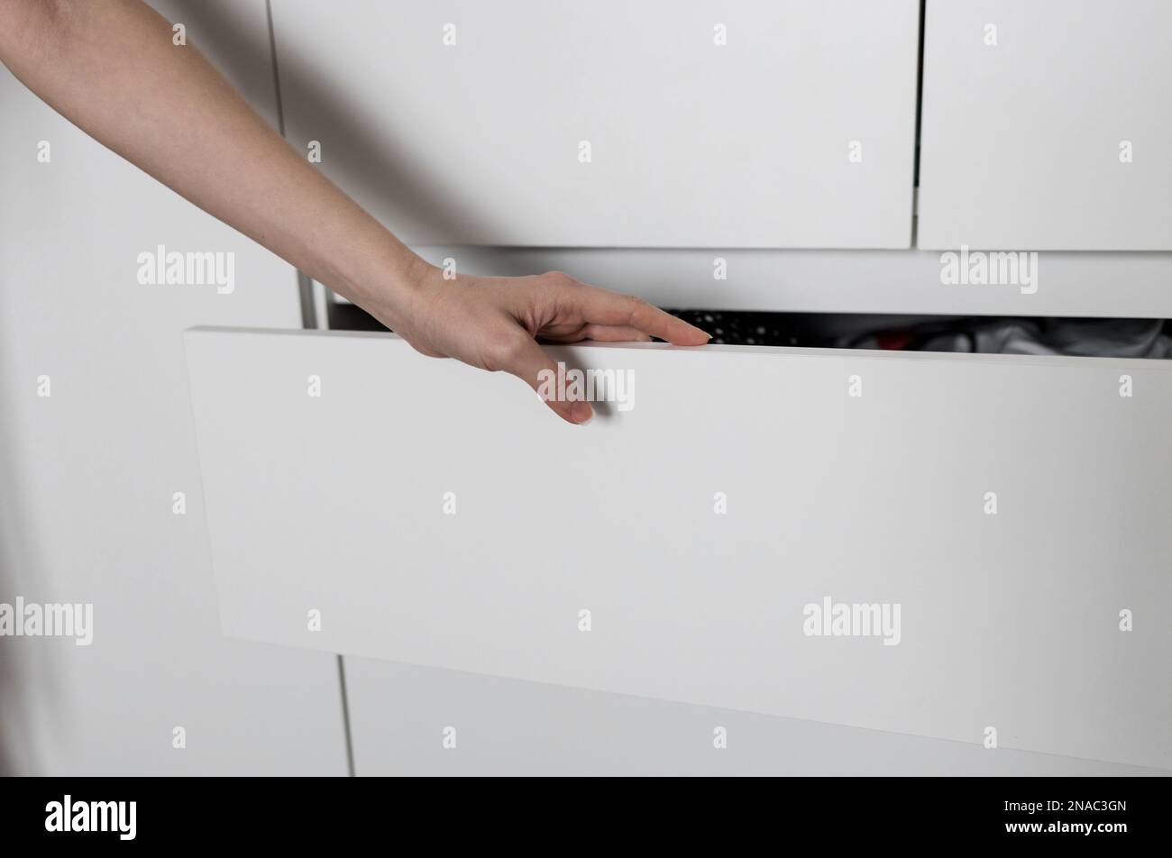 hand pulls out a shelf in a white cabinet. close up hand opening drawer Stock Photo - Alamy