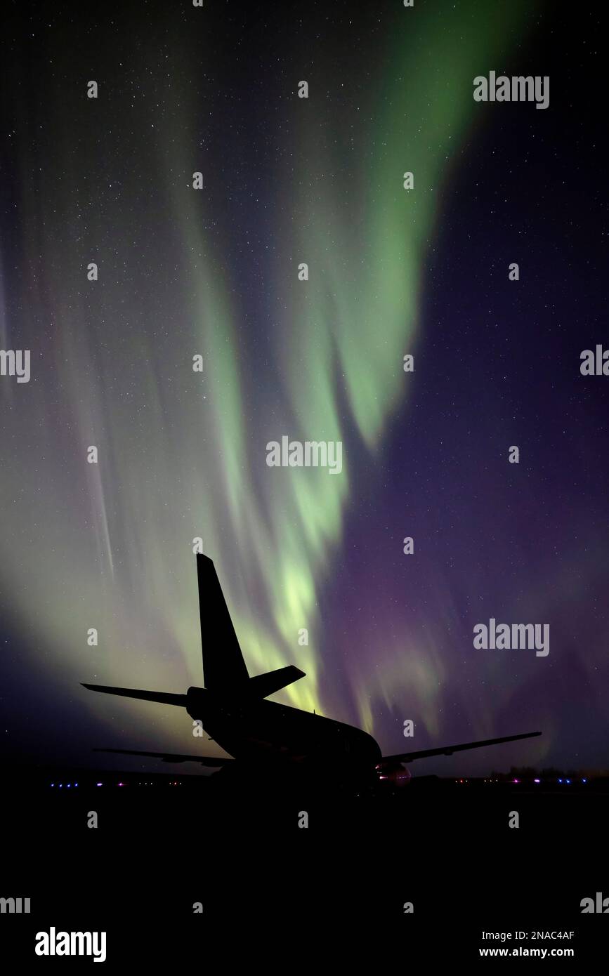 Silhouetted airplane with Aurora Borealis in the starry night sky ...