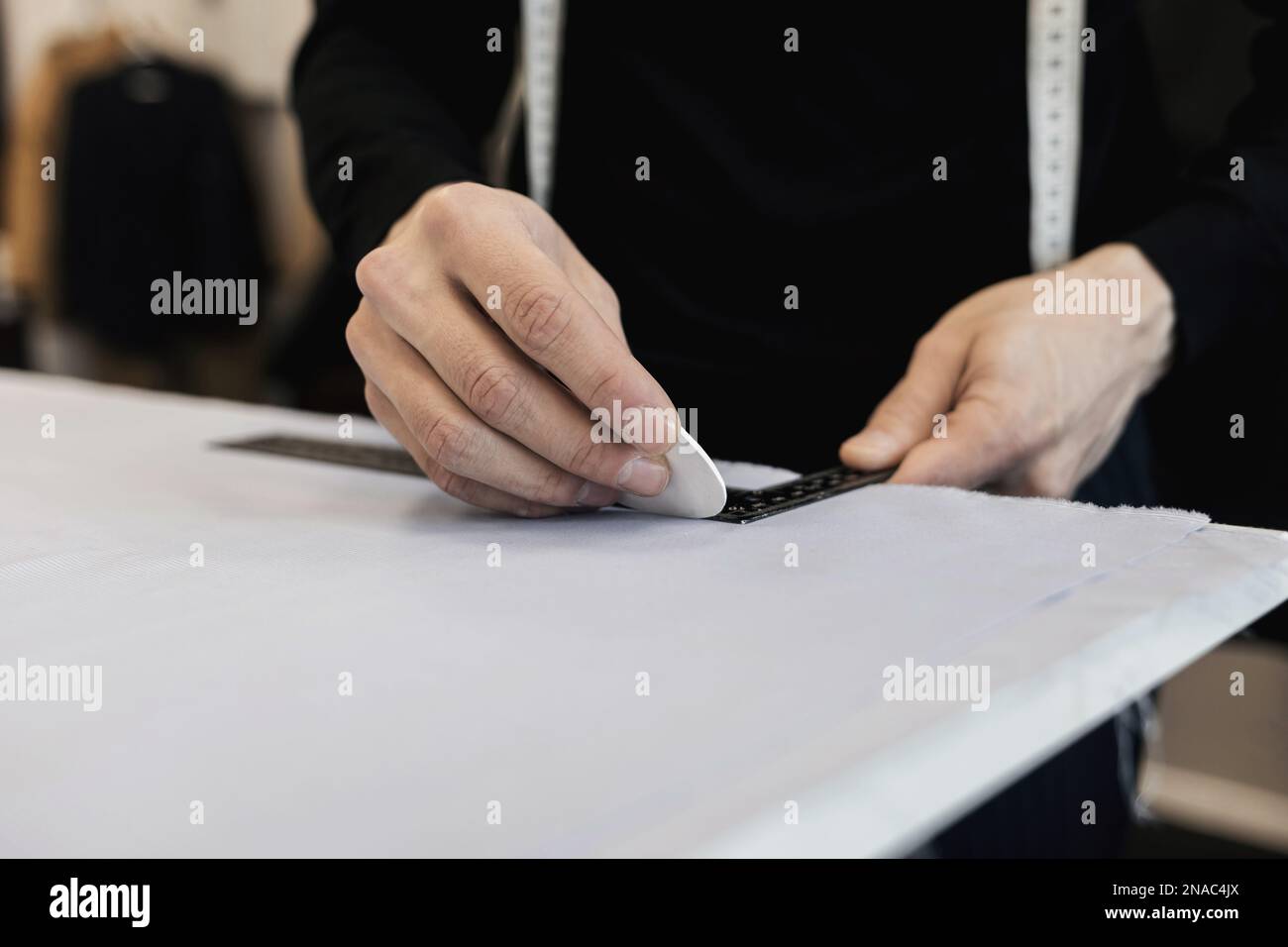 Tailor using chalk to mark a pattern on to a length of fabric. handmade ...