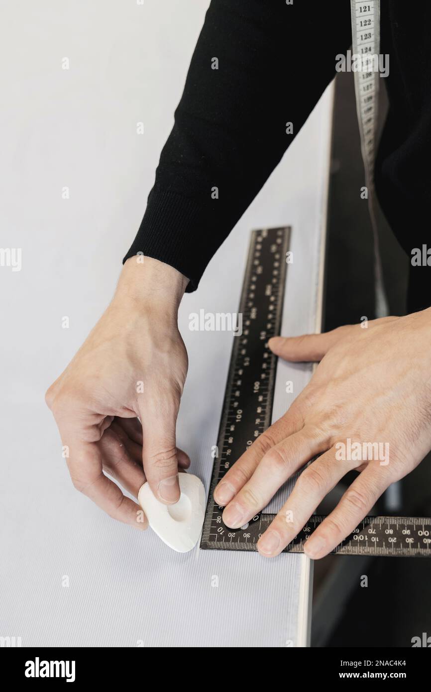 tailor with a ruler and chalk marks clothes. hand of professional ...