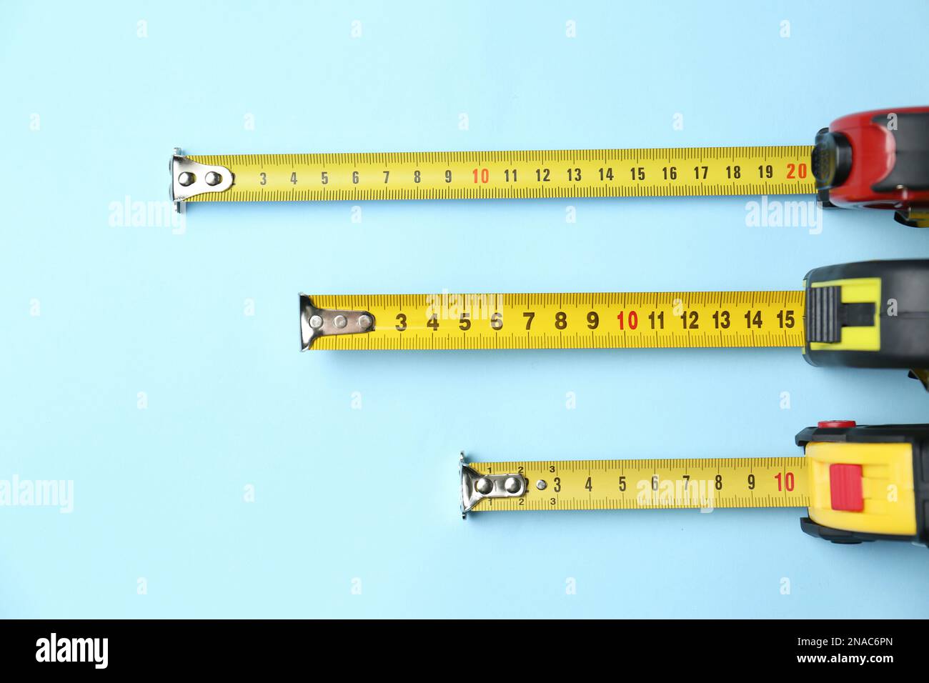 Tapes measure on light blue background, flat lay. Construction tool ...