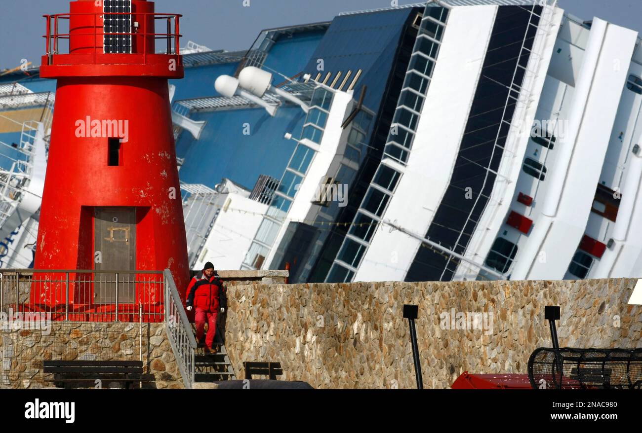 An Italian firefighter walks near a lighthouse at the entrance of the ...