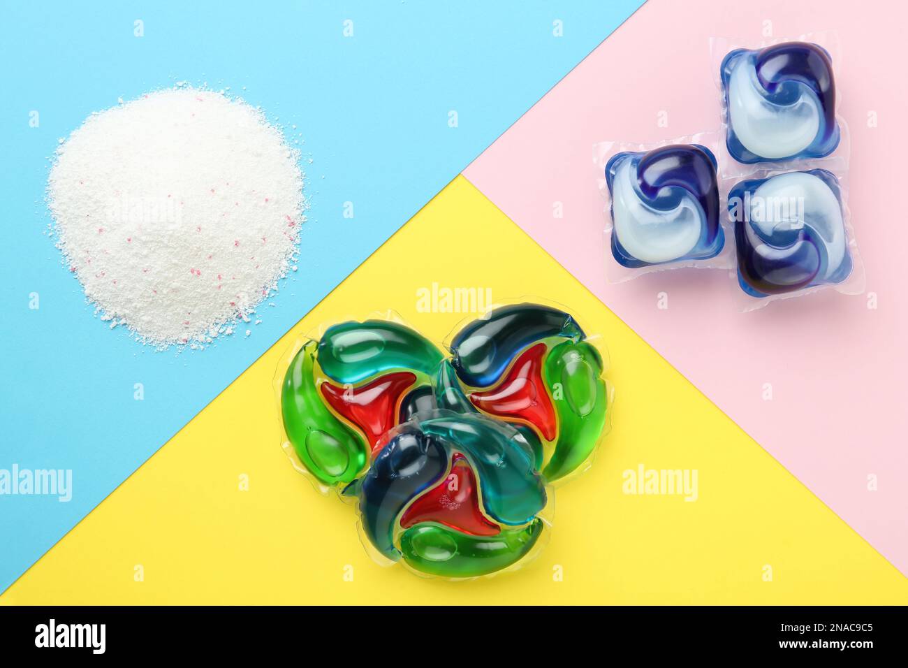 Different laundry capsules and washing powder on color background, flat ...