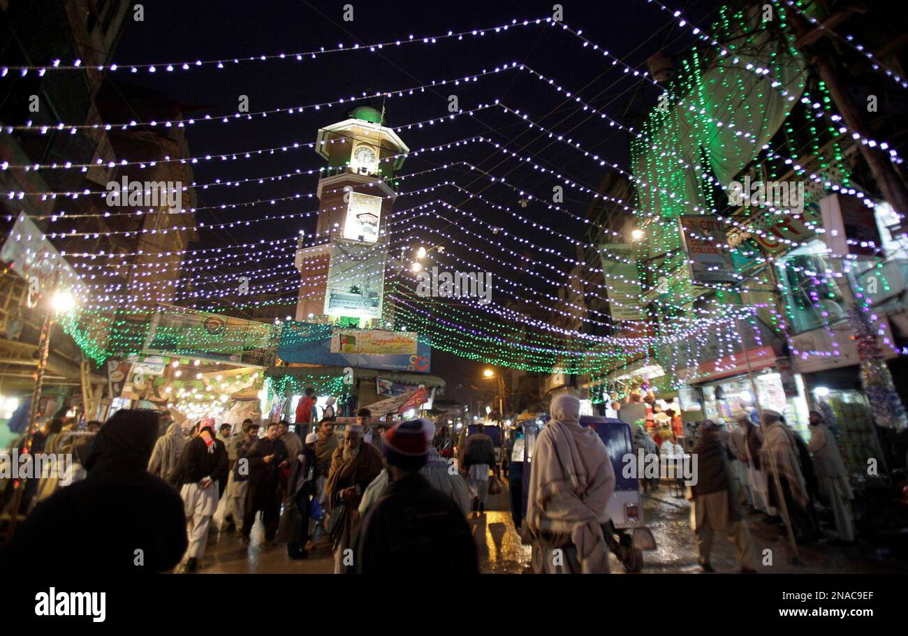 Pakistani Muslims walk on a street decorated with festive lights on the ...