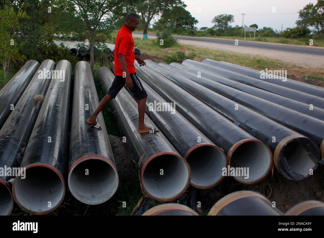 A young South African man walks on giant water pipes near the Limpopo ...
