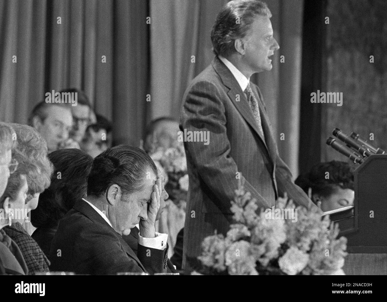 U.S. President Richard Nixon has his eyes closed and a hand to his head ...