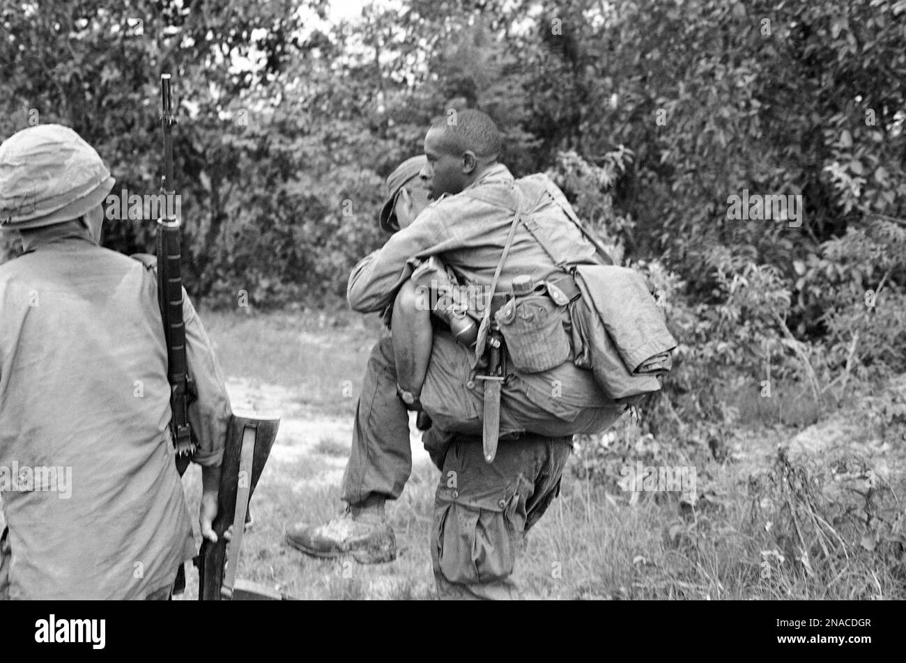A wounded private clings to the back of an army major who carries him ...