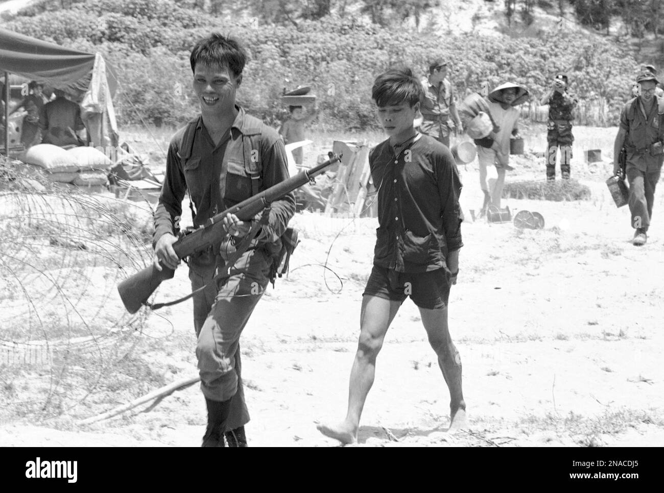 A happy South Vietnamese soldier brings a Viet Cong prisoner into the ...