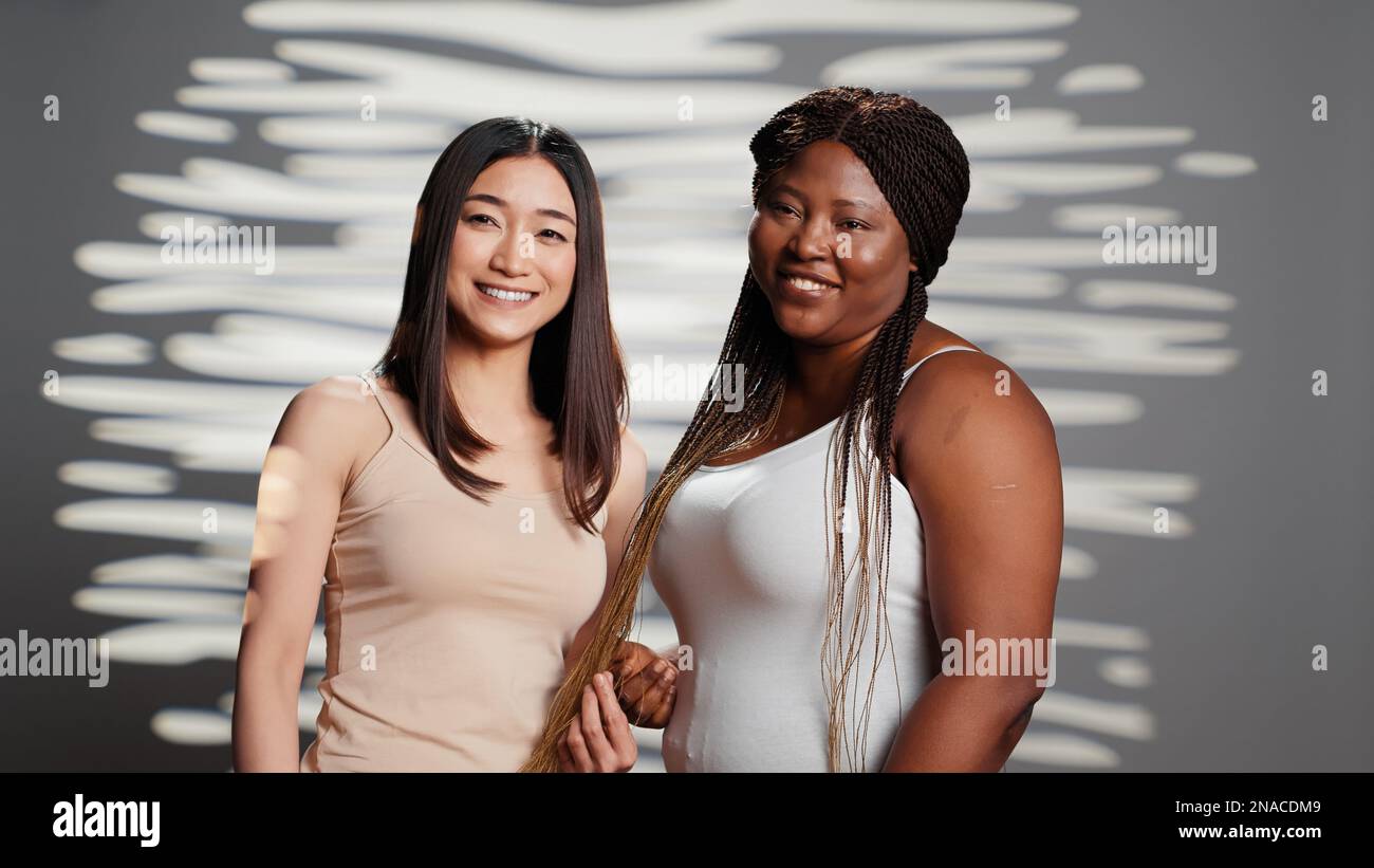 Interracial unique women creating beauty ad in studio, promoting ...
