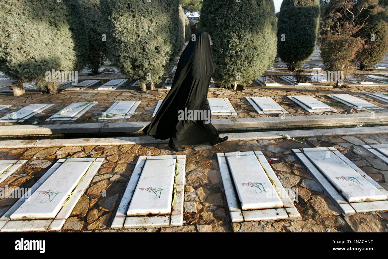 A veiled Iranian woman, walks past the graves of unknown soldiers, who ...
