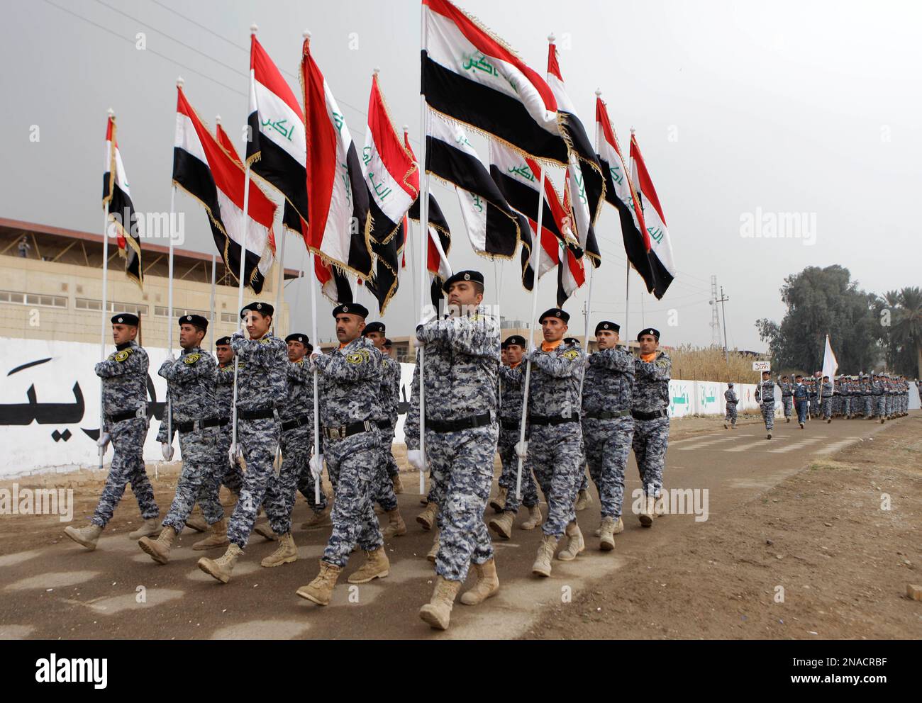 Iraqi federal police graduates march holding national flags during ...