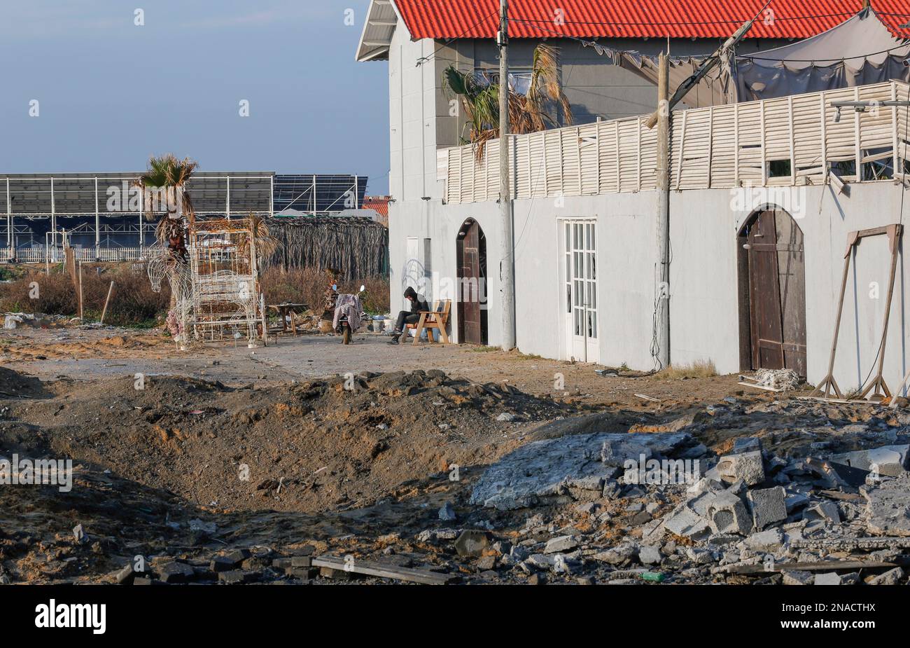 A Palestinian man sits near a destroyed wedding hall after being ...