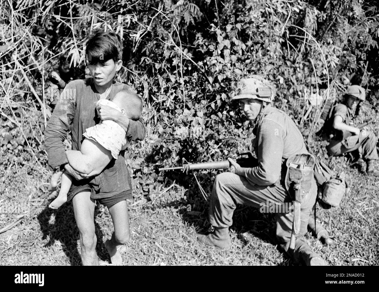 Vietnamese man carrying a child is followed out of jungle as a U.S. 1st ...