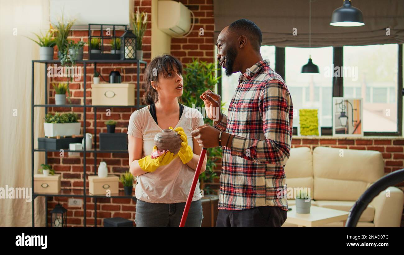 Diverse husband and wife cleaning household with vacuum and rags, woman ...