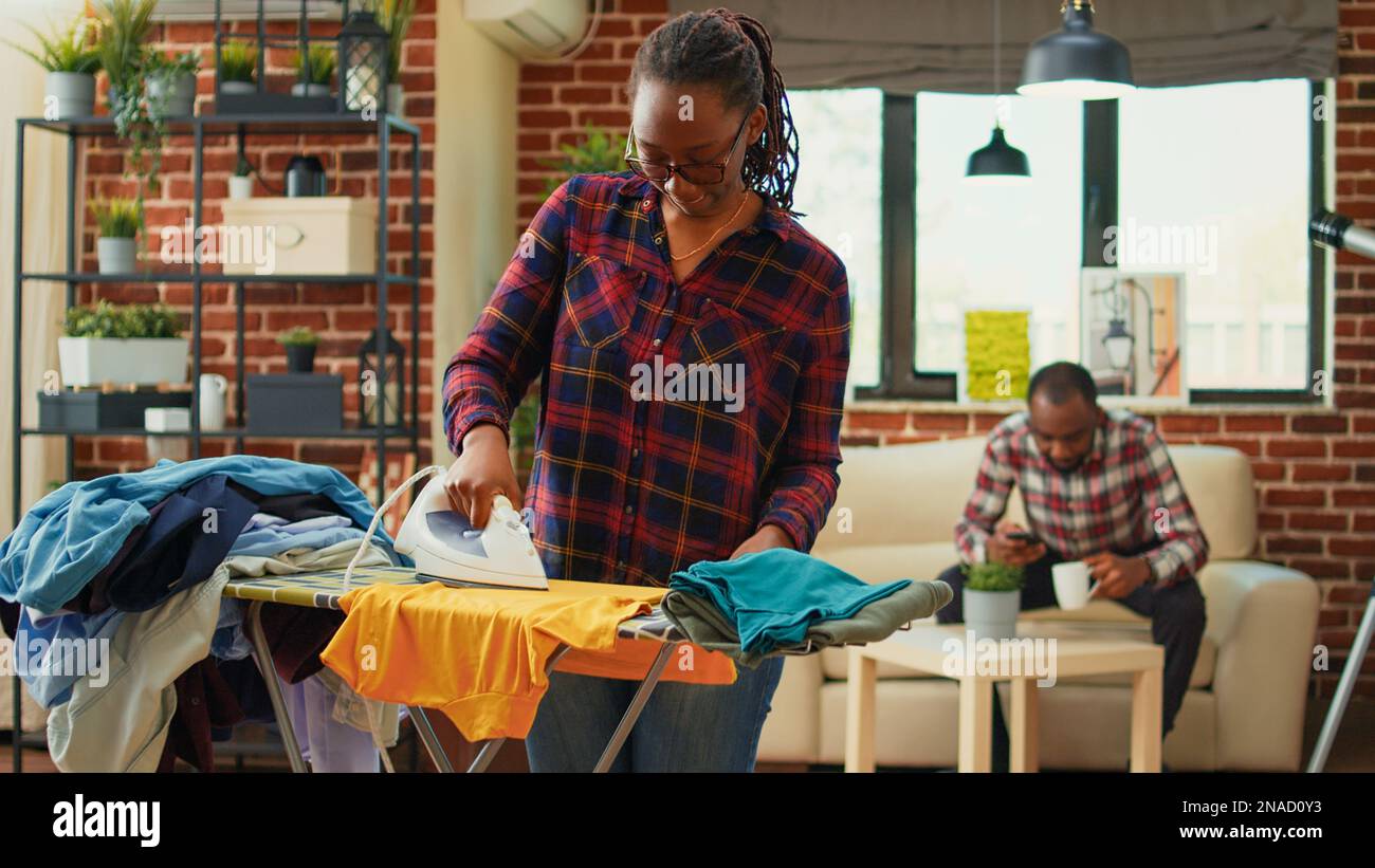 African american girl using steam on ironing board to do domestic work ...