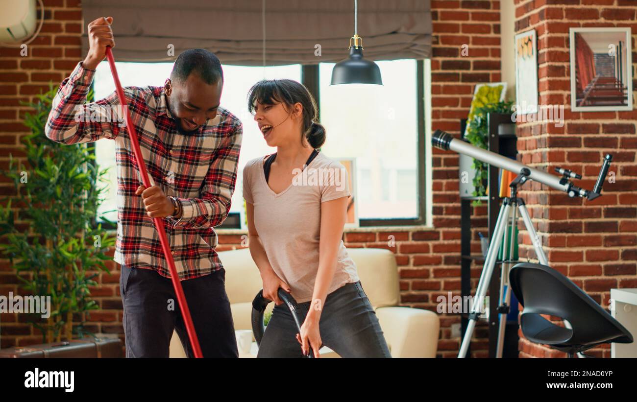 Interracial couple showing dance moves and having fun spring cleaning ...