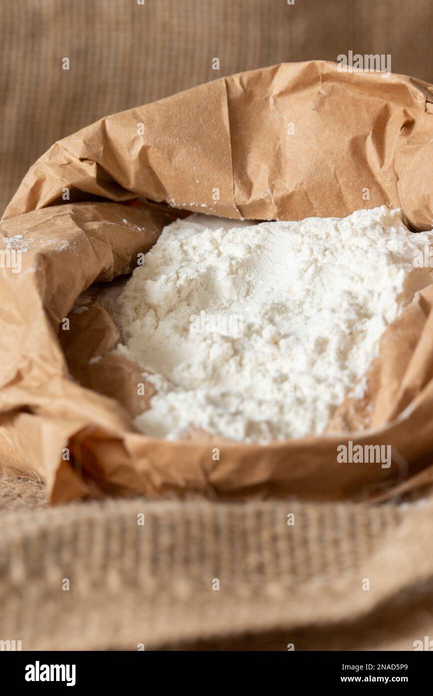 Plain white flour in a brown paper bag on hessian sack cloth. Eco ...