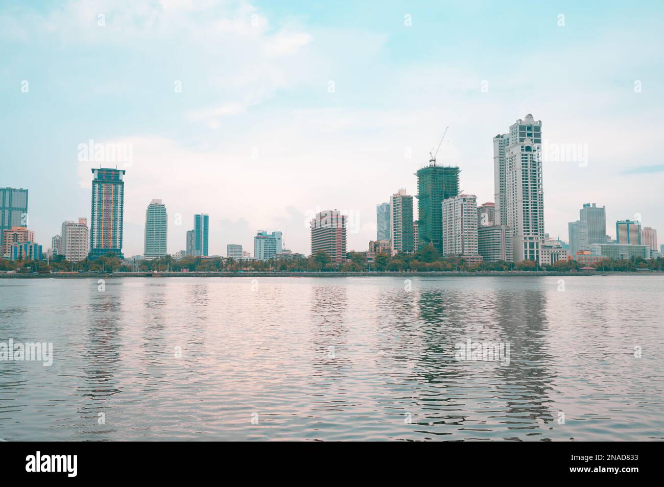 The calm waters of the sea with the buildings of Manila City of the ...
