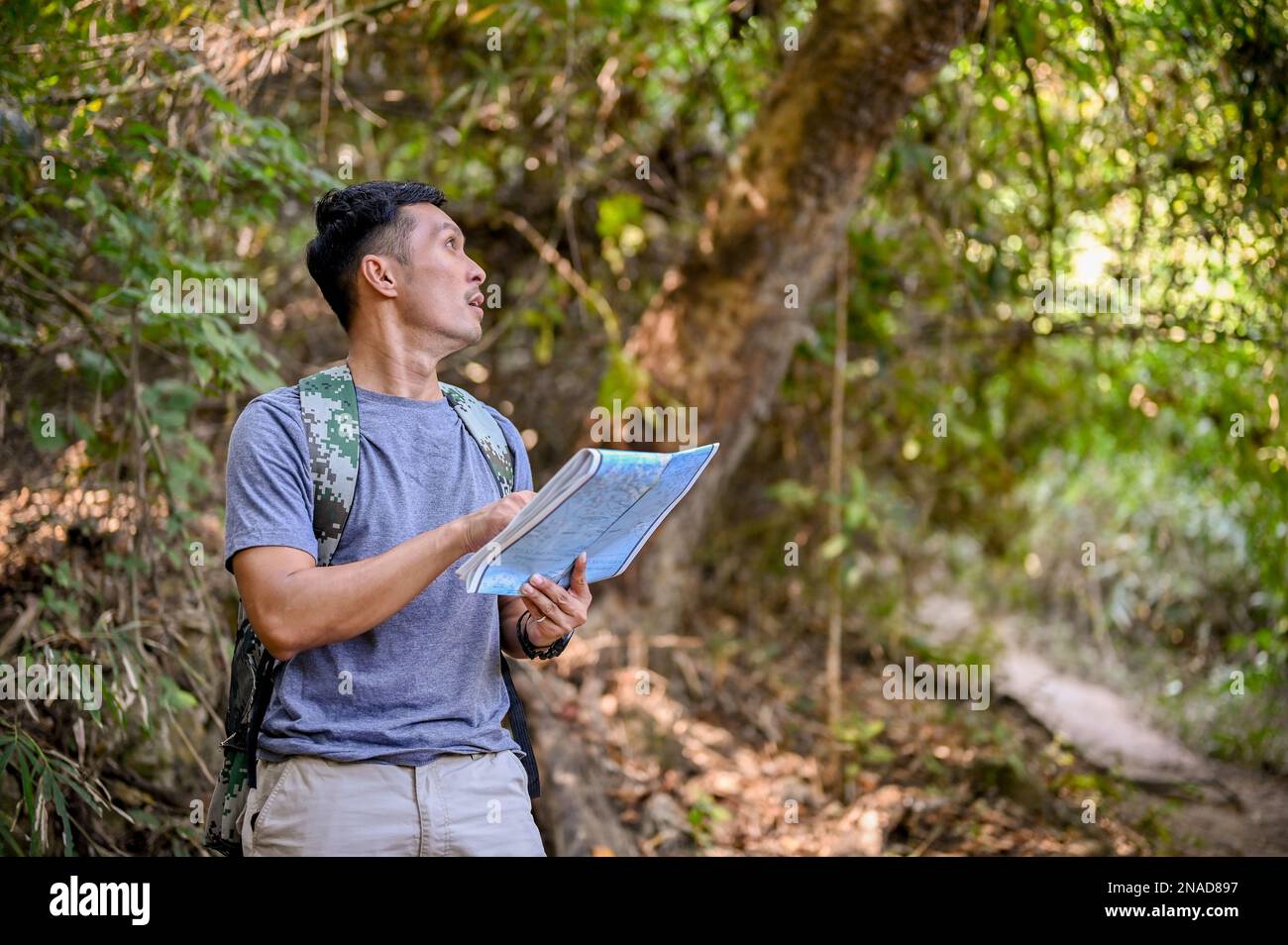 Active fit Asian male trekker or traveler with a backpack looking at ...