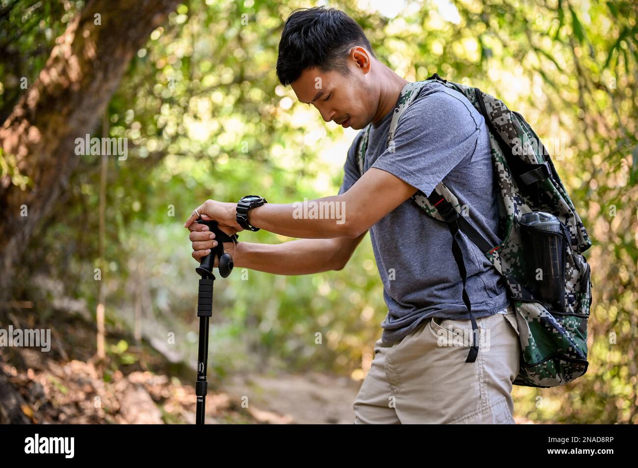 Tired and exhausted Asian male traveler with trekking gear and backpack ...