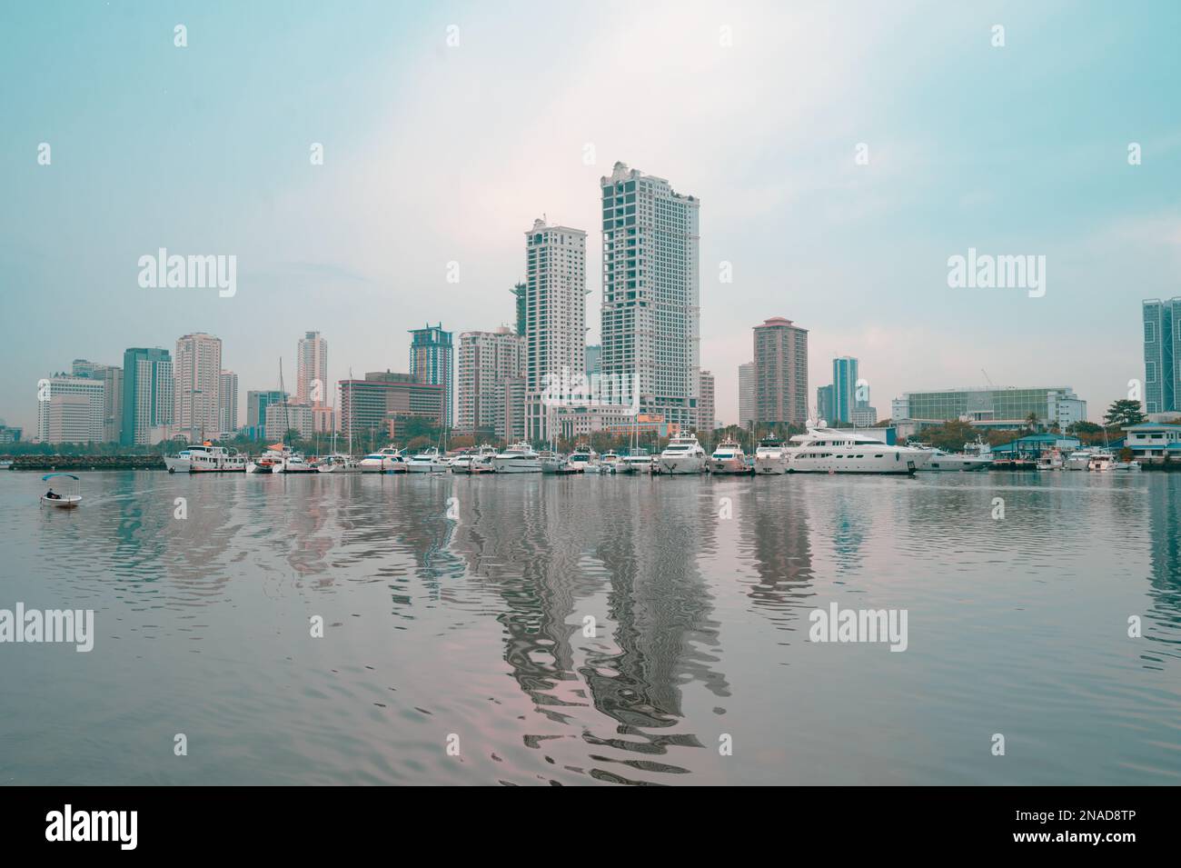 The calm waters of the sea with the buildings of Manila City of the ...