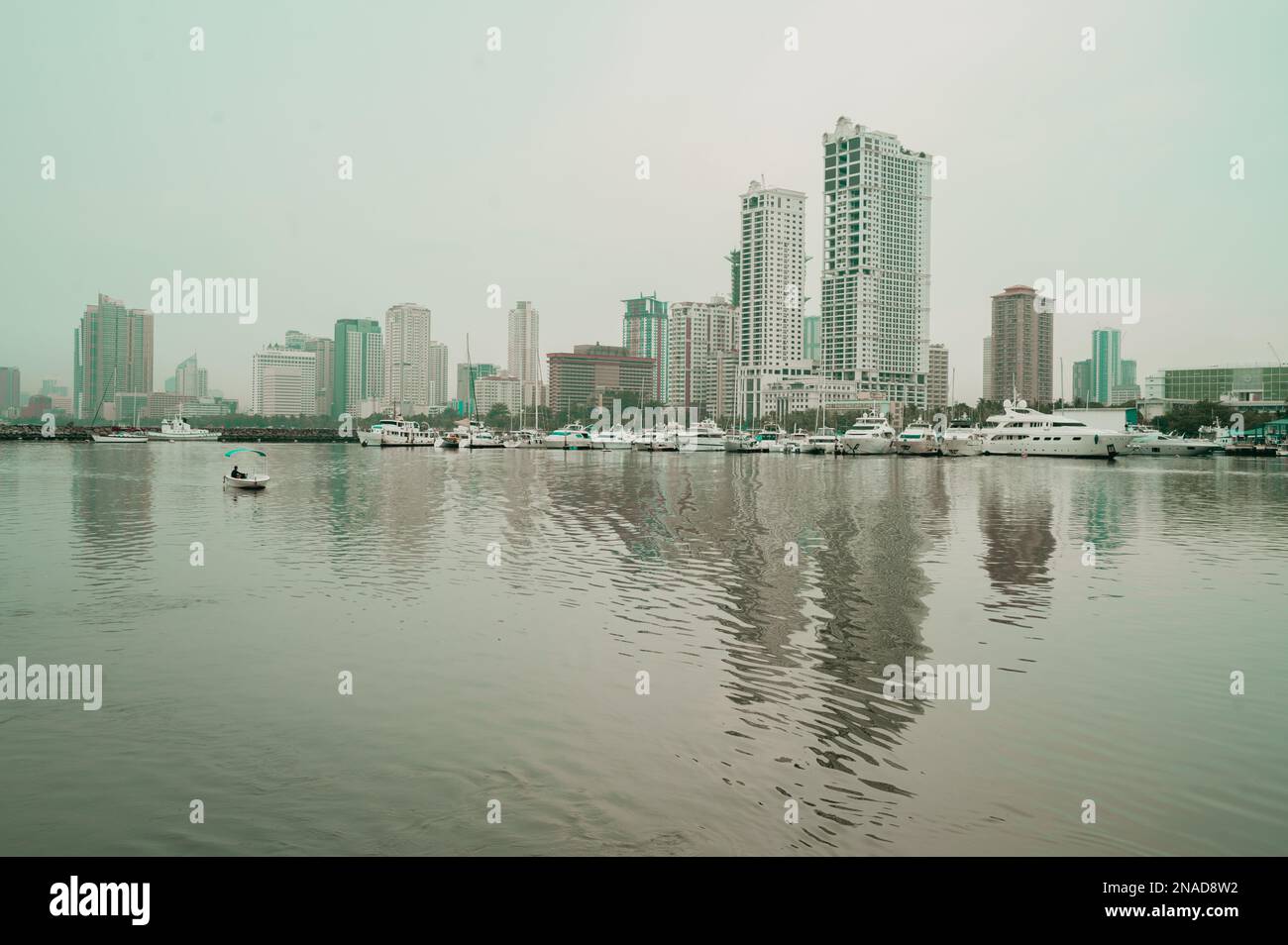 The calm waters of the sea with the buildings of Manila City of the ...