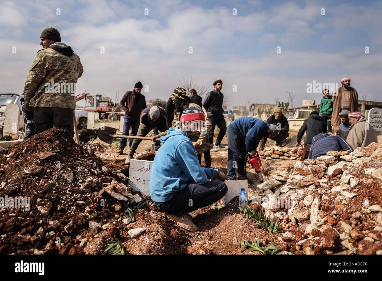 Idlib, Syria. 13th Feb, 2023. A Syrian sits next to a grave during the ...