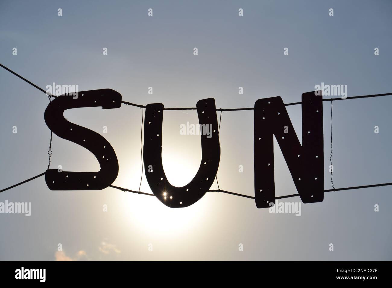 The word SUN with metallic letters hanging against the sky with a ...