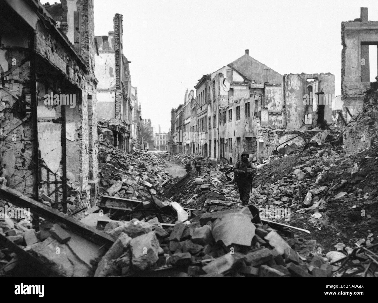 An American soldier picks his way through the debris of a wrecked ...