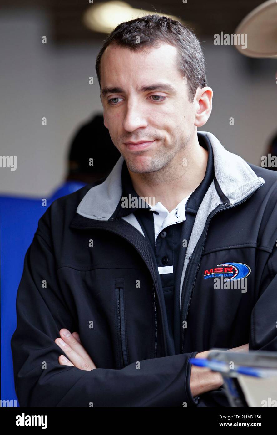 Driver Justin Wilson, of England, stands in his garage during a ...