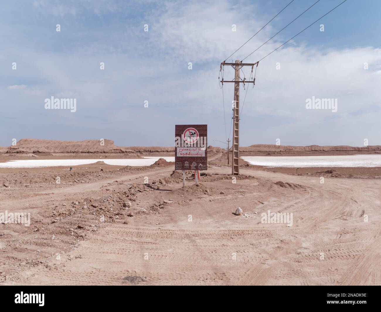 A desert landscape featuring an empty dirt road with a signpost in the ...