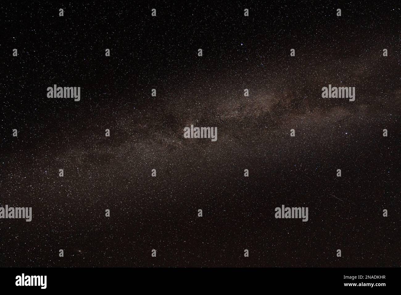 A tranquil night sky featuring white stars and clouds illuminated by a ...