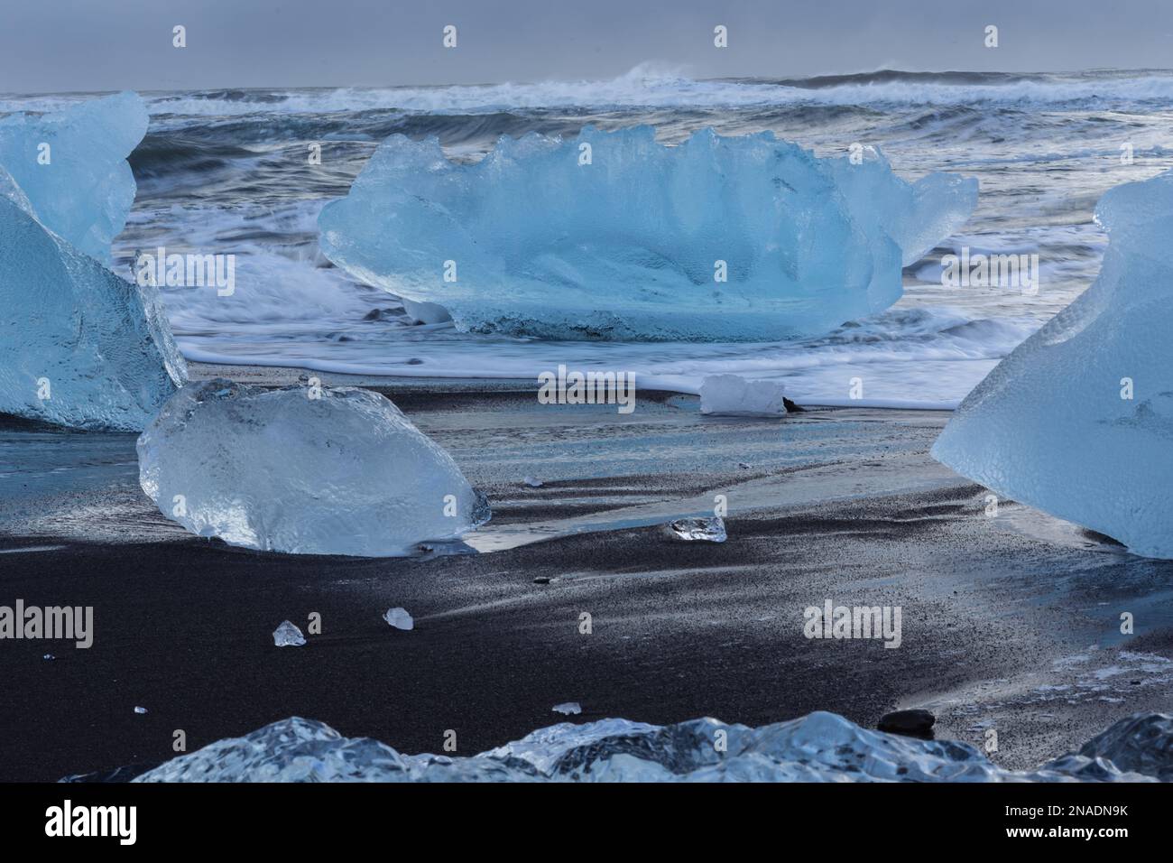 A scenic view of a beach with small pieces of ice scattered in the sand ...