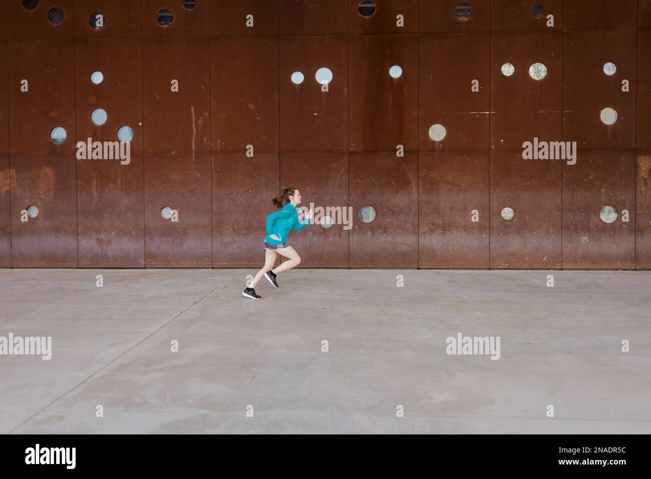Young woman running along concrete wall in the city Stock Photo - Alamy