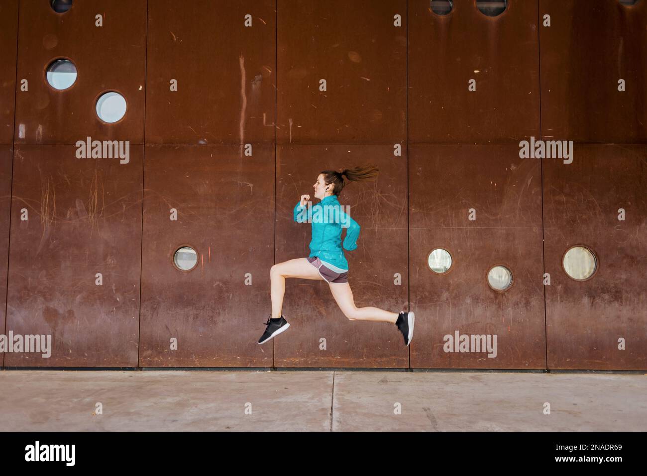 Side view of young runner woman sprint and jumping against wall Stock ...