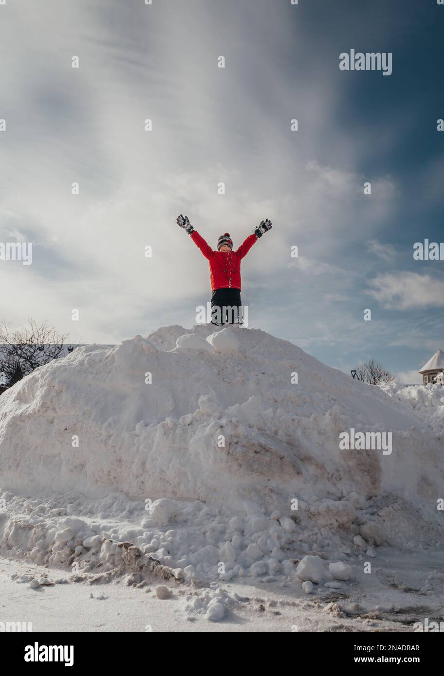 Happy boy standing on top of a big snow pile on winter day Stock Photo ...