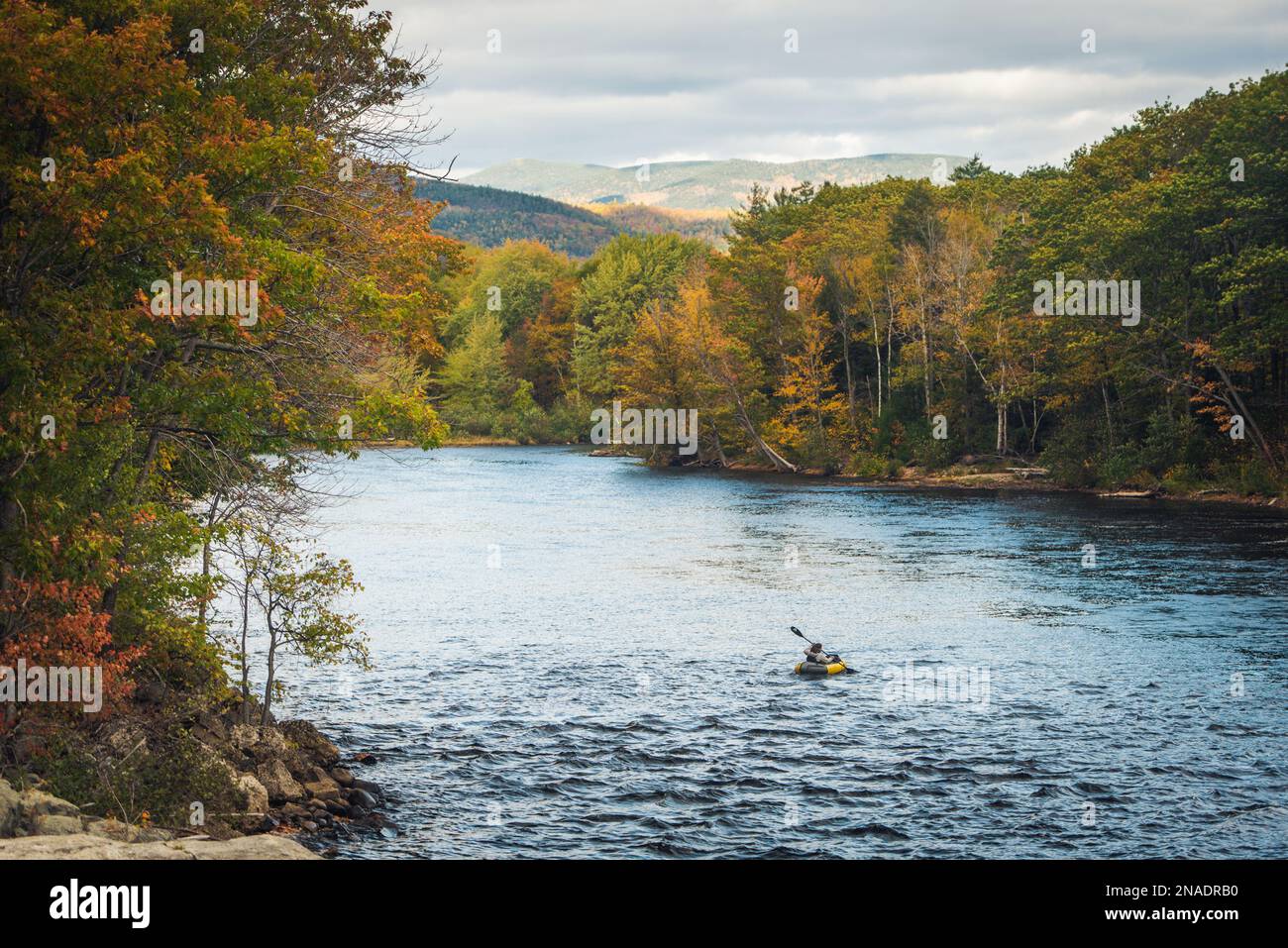A woman paddling down river in a pack-raft in fall foliage Stock Photo ...