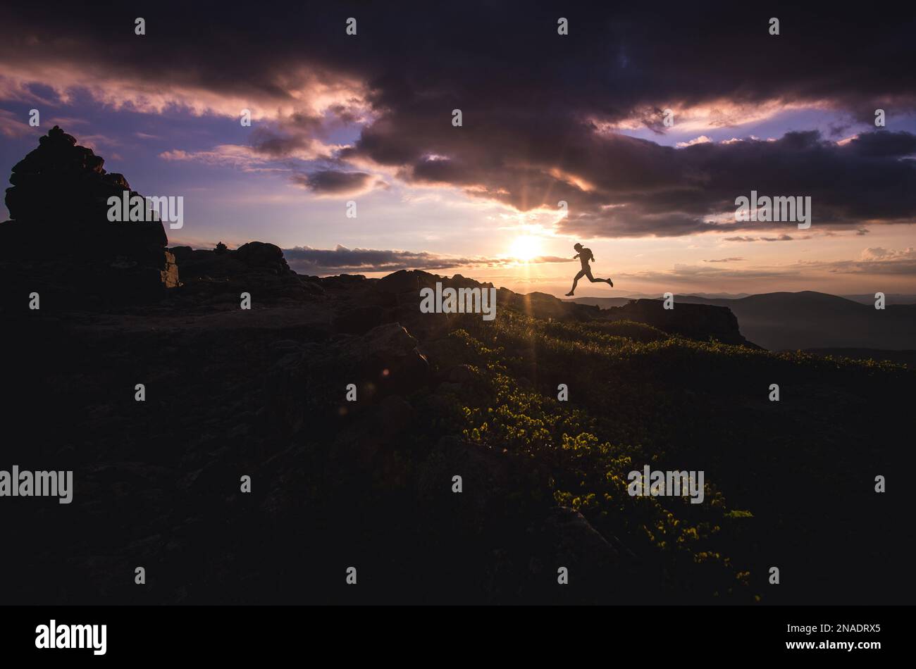 Silhouetted trail runner man jumping between rocks Stock Photo - Alamy