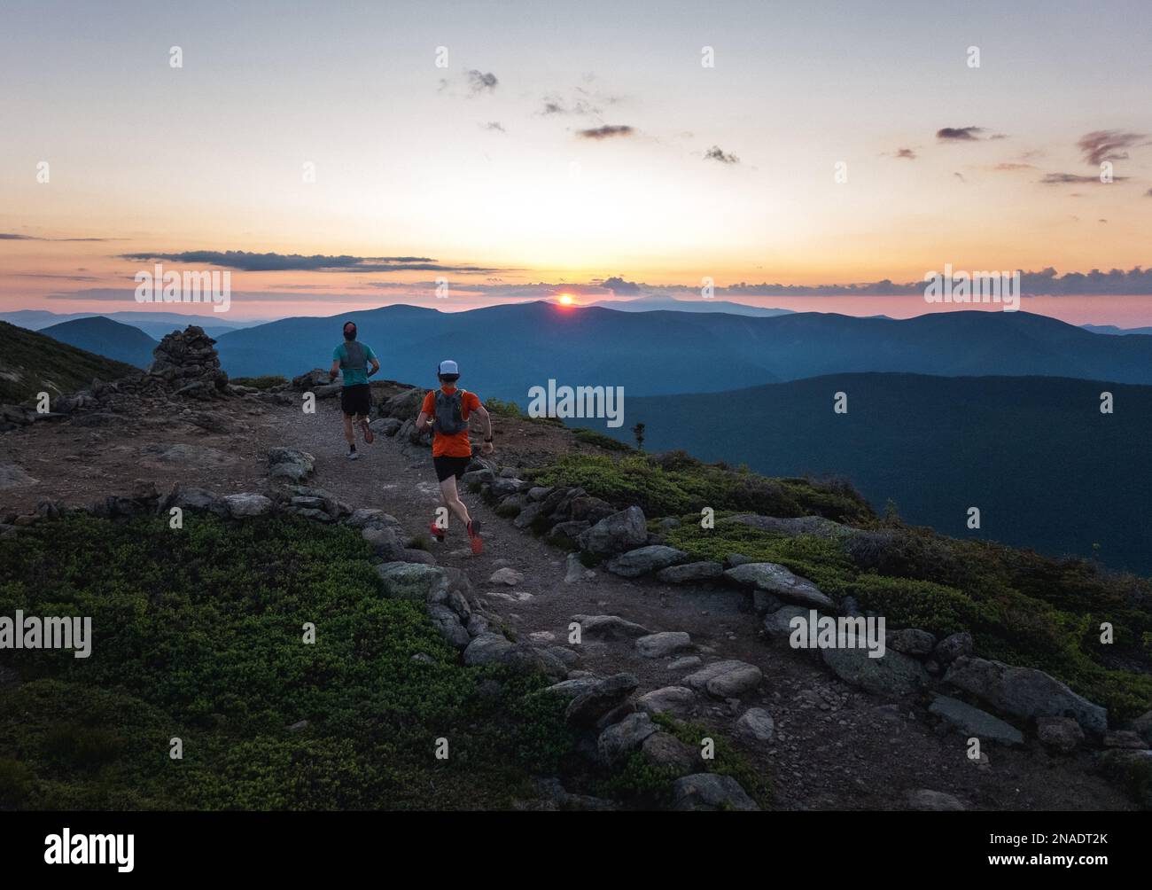 Two trail runner men running a path at sunrise with mountains Stock ...