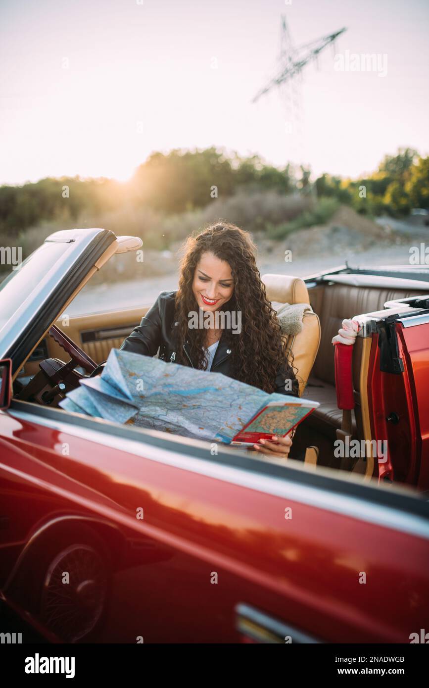 Woman with curly hair sitting in a vintage car, looking at the m Stock ...