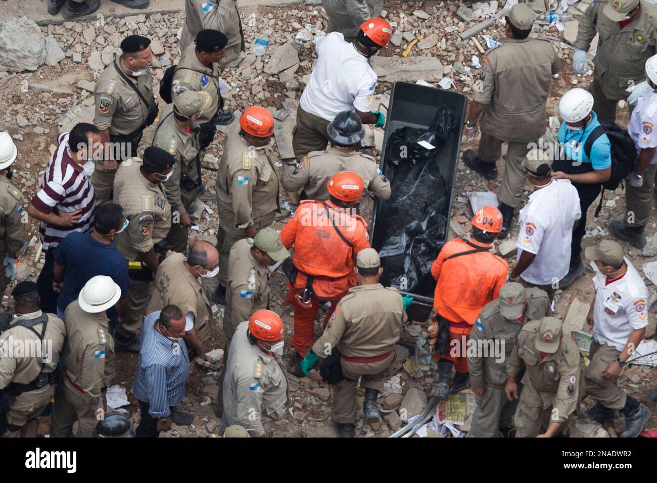 Rescue workers carry the body of a victim after a building collapsed in ...