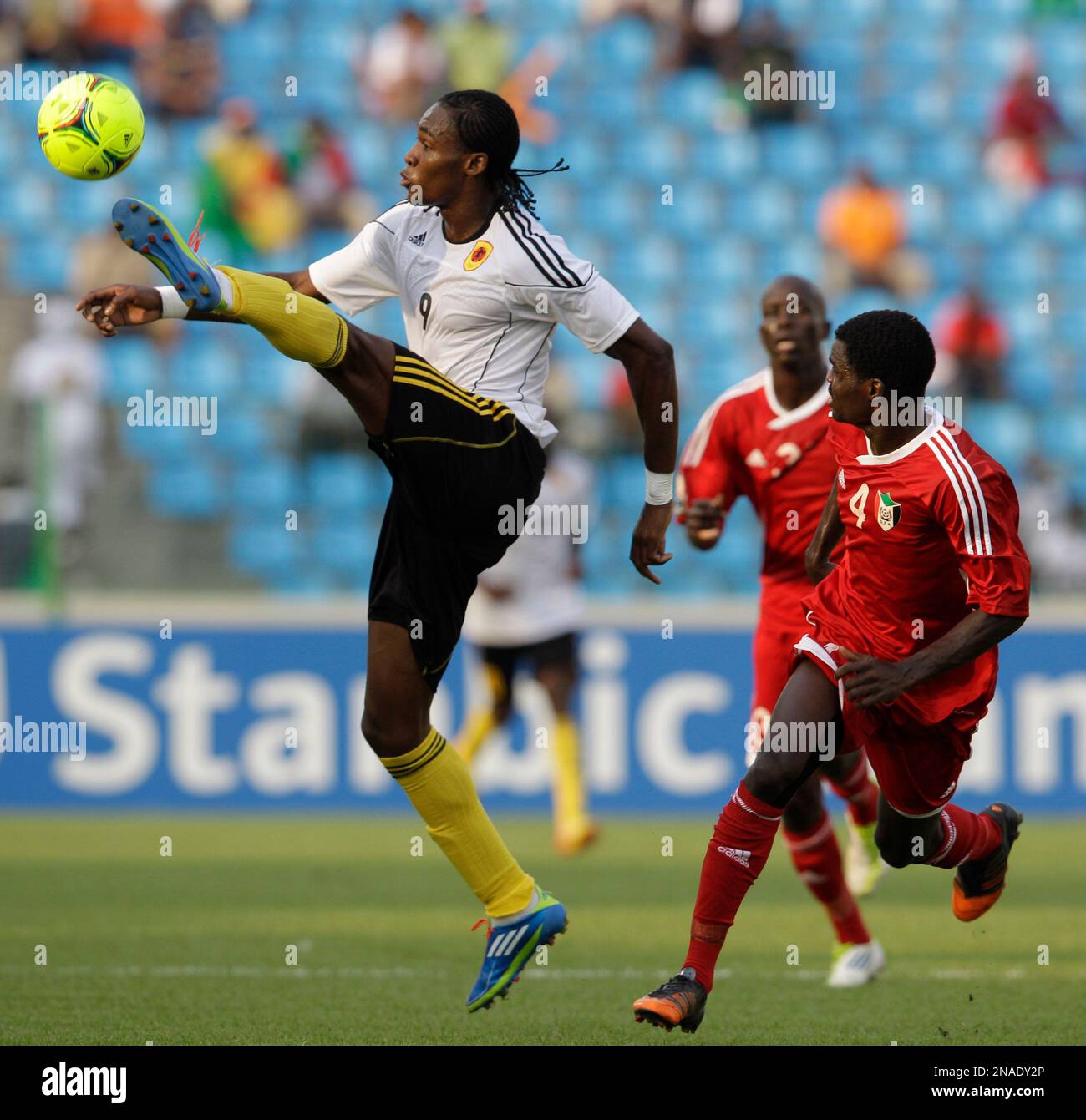 Angola's Manucho kicks the ball past Sudan's Ngam Eldin Abdullah, right ...