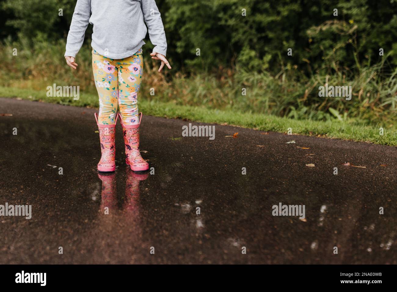 Young girl stands in puddle outside on walking path during Fall Stock ...