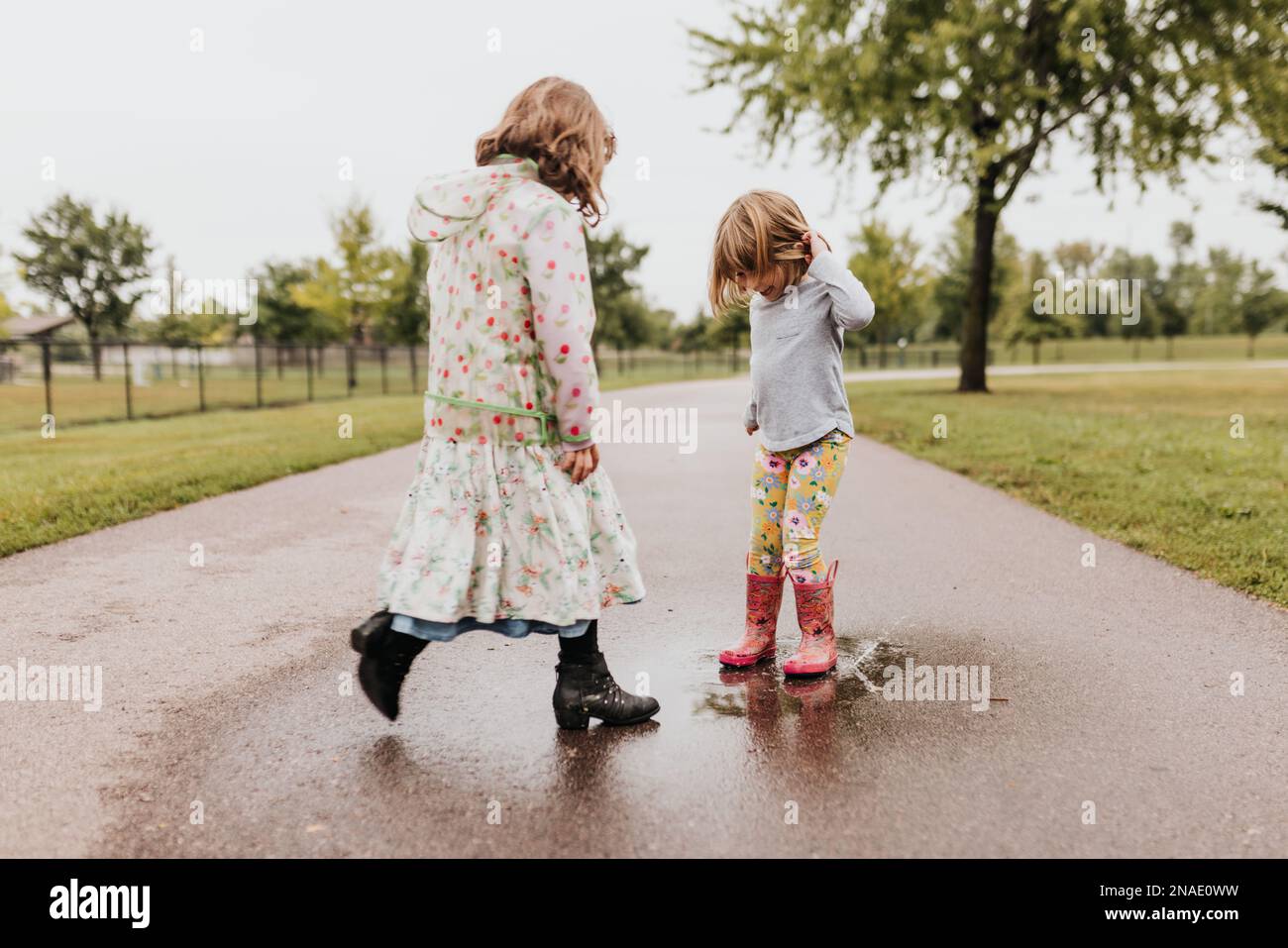 Sister's splash in a puddle on a walking trail outside after a rain ...