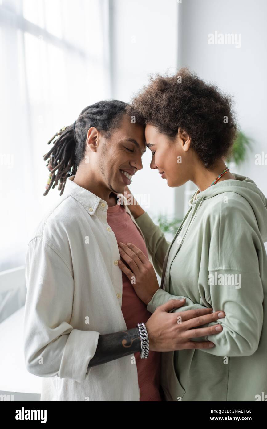 Positive African American Couple Hugging With Closed Eyes At Home Stock