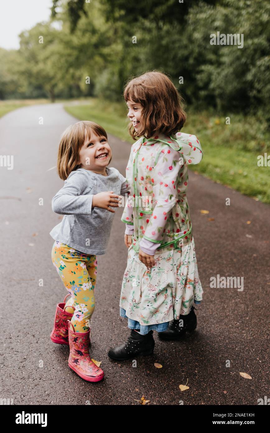 two young girls play and laugh along walking trail on a fall morning ...